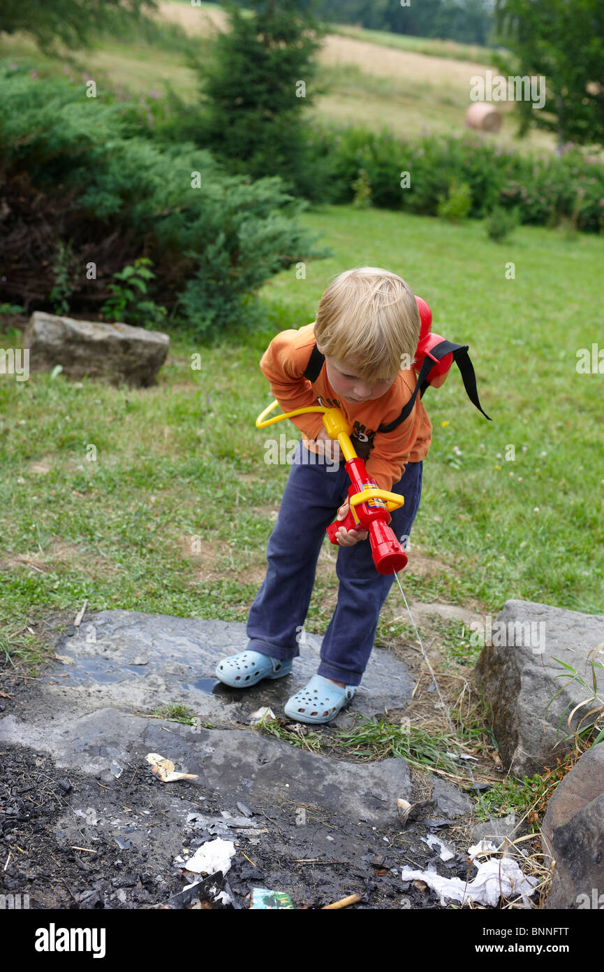 Young child boy playing fire fighter garden Stock Photo - Alamy