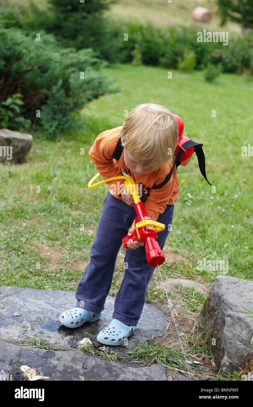 Young child boy playing fire fighter garden Stock Photo - Alamy