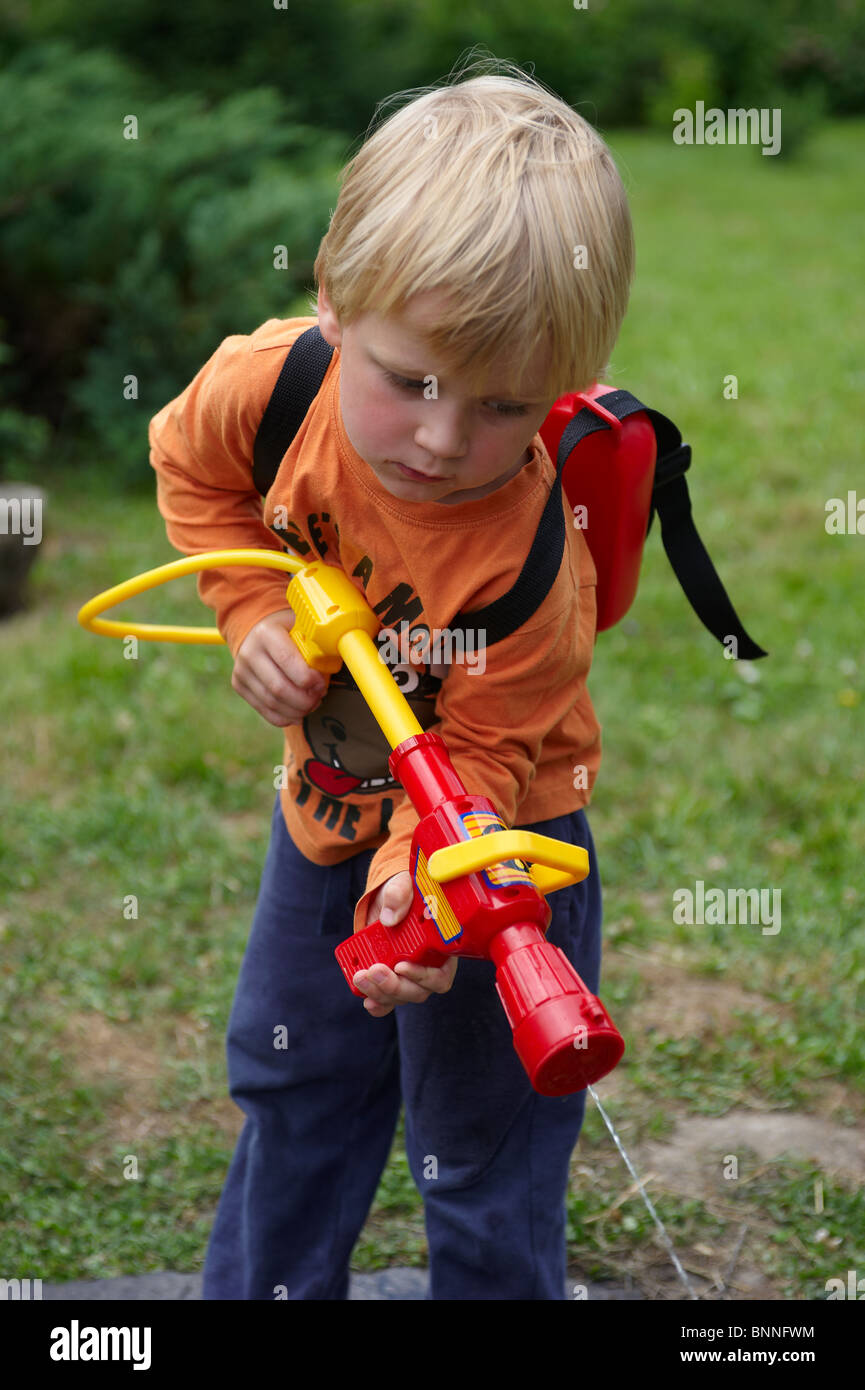 Young child boy playing fire fighter garden Stock Photo - Alamy