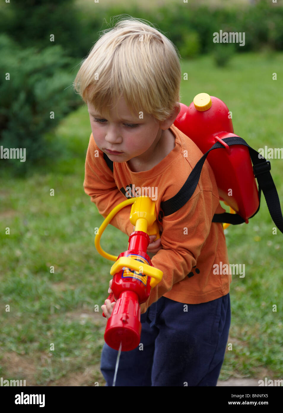 Young child boy playing fire fighter garden Stock Photo - Alamy