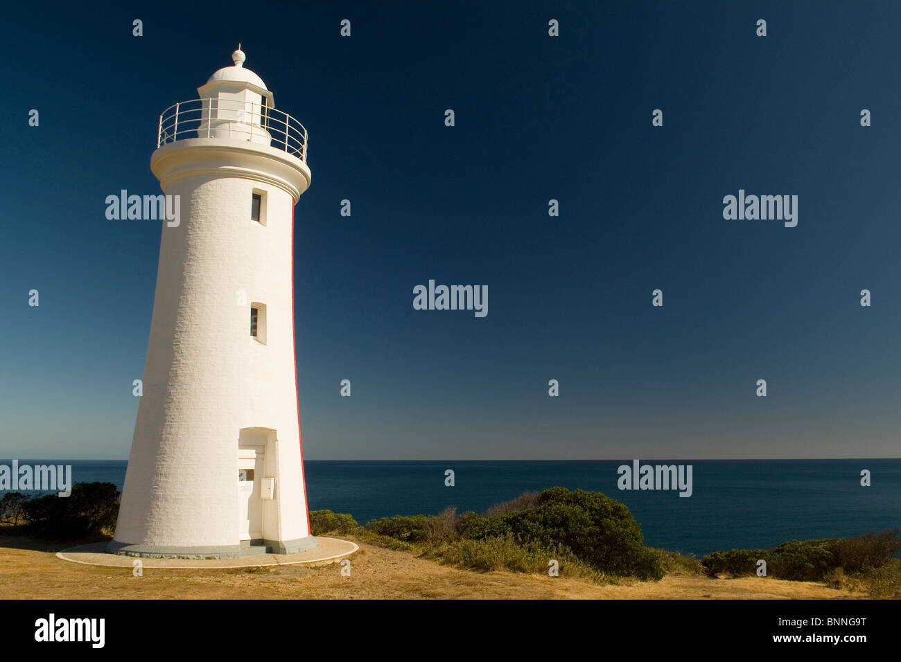 Grand white washed lighthouse looks over the deep blue ocean Stock ...