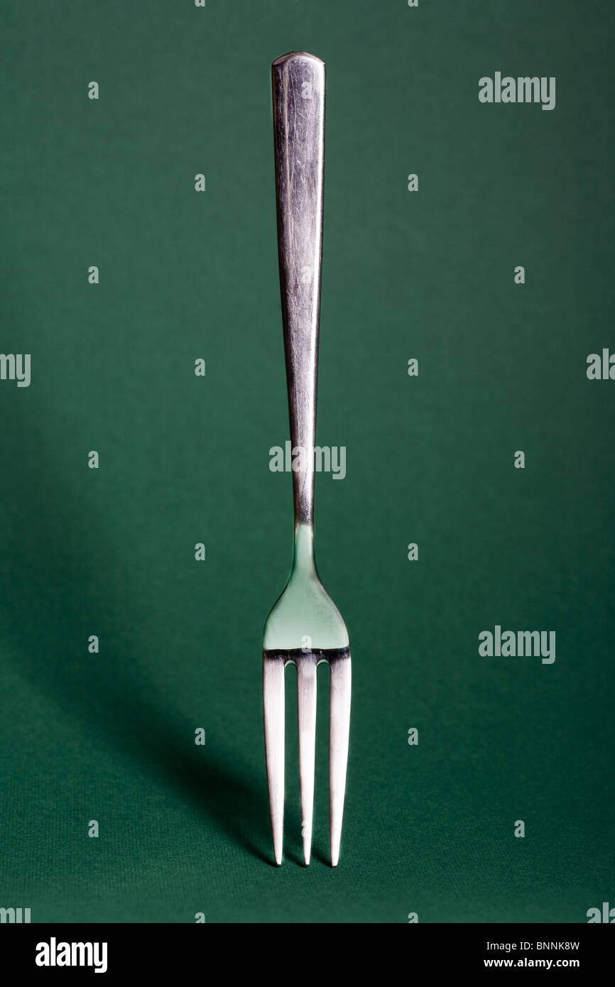 metal fork isolated on green background Stock Photo - Alamy