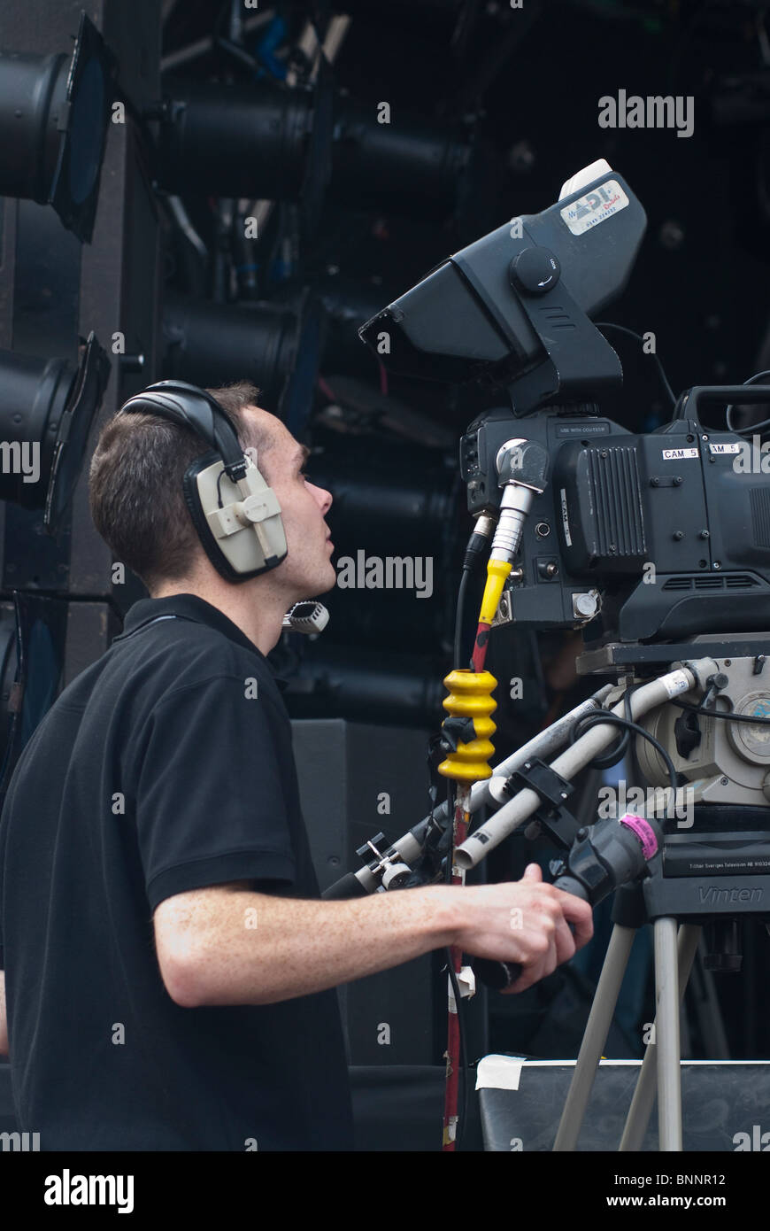 Camera operator recording live event, camera on tripod Stock Photo - Alamy