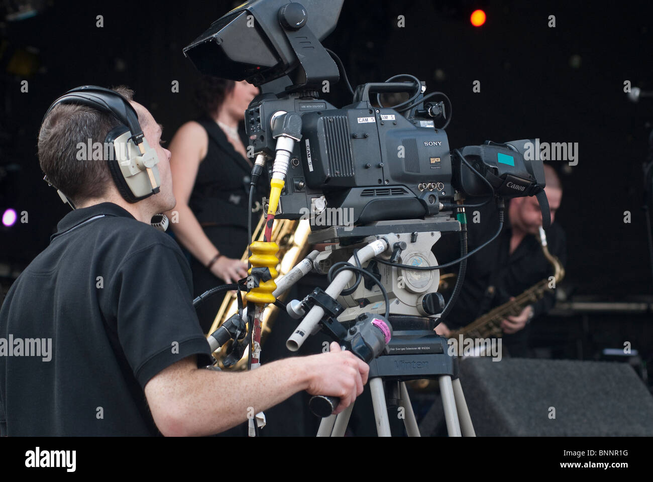 Camera operator recording live event, camera on tripod Stock Photo - Alamy