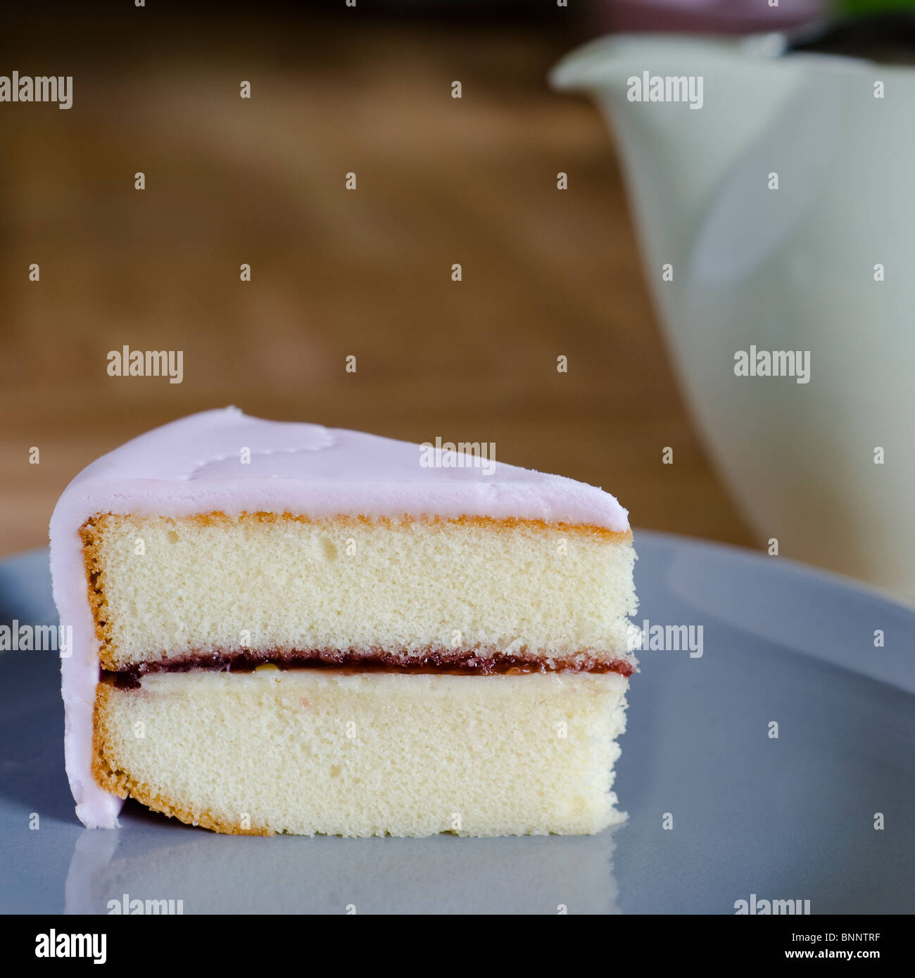 Still life of a slice of cake with a teapot in the background Stock ...