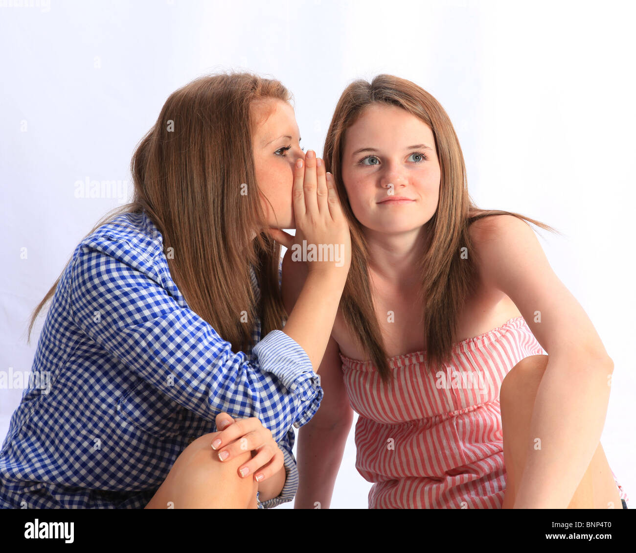 2 teenage girls sisters twins friends whispering Stock Photo - Alamy