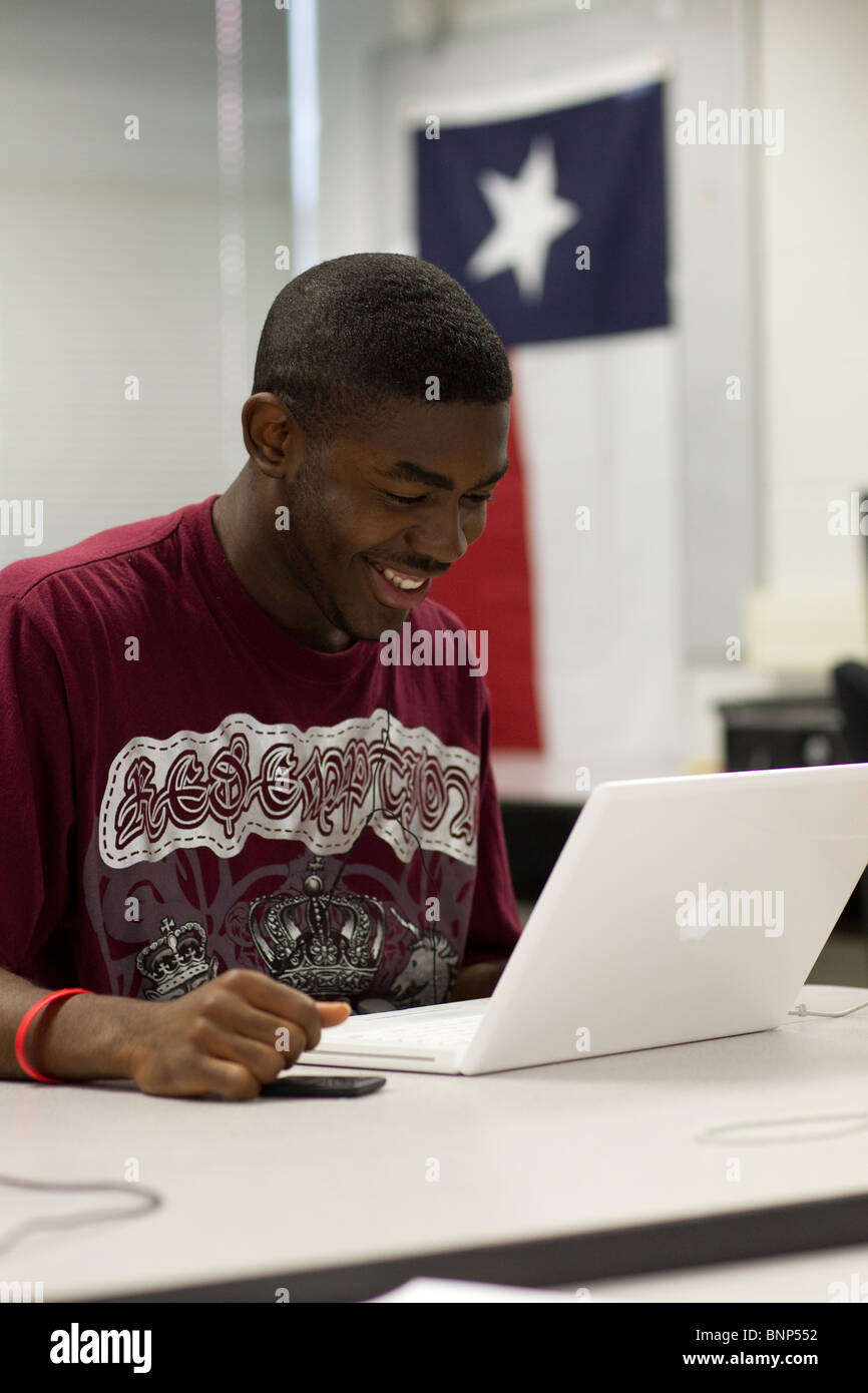 African-American boy uses MacBook laptop computer to do classwork at ...