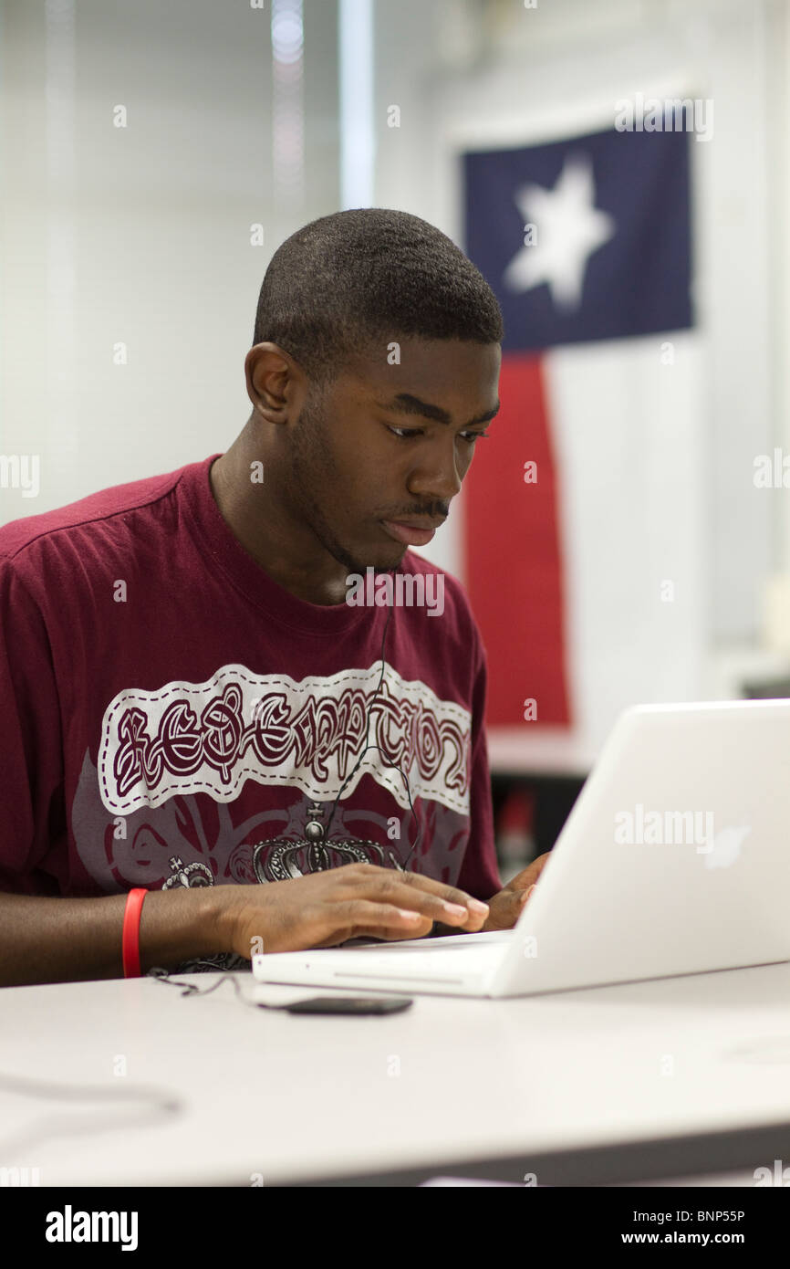 African-American boy uses MacBook laptop computer to do classwork at ...