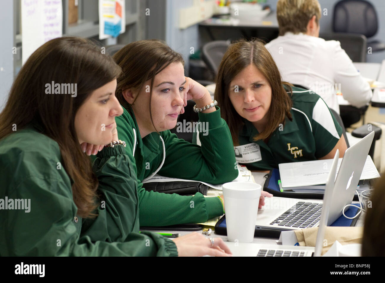 Female high school teachers use laptop computers to collaborate on ...