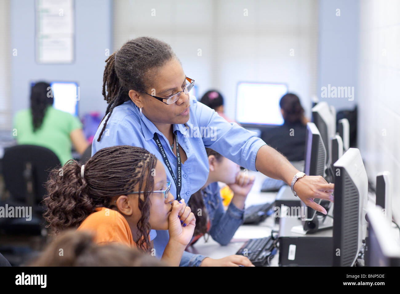 African-American female teacher instructs student using computer during ...