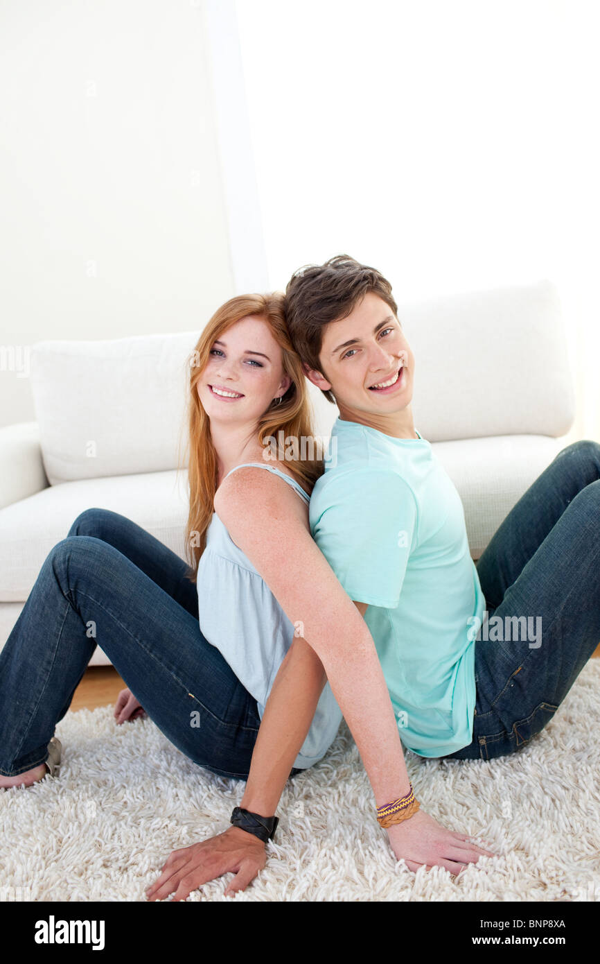 A smiling couple of teenagers sitting on the floor Stock Photo - Alamy