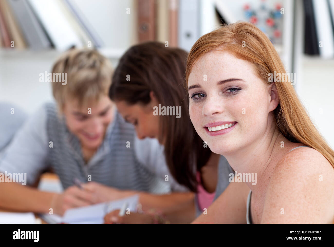 Teen girl studying in the library with her friends Stock Photo - Alamy