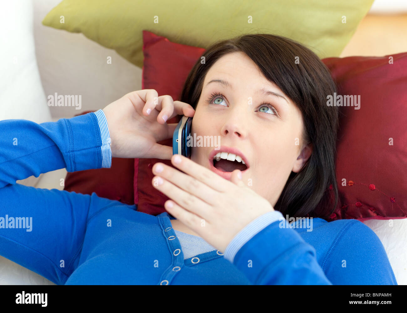 Surprised teen girl talking on phone lying on a sofa Stock Photo - Alamy
