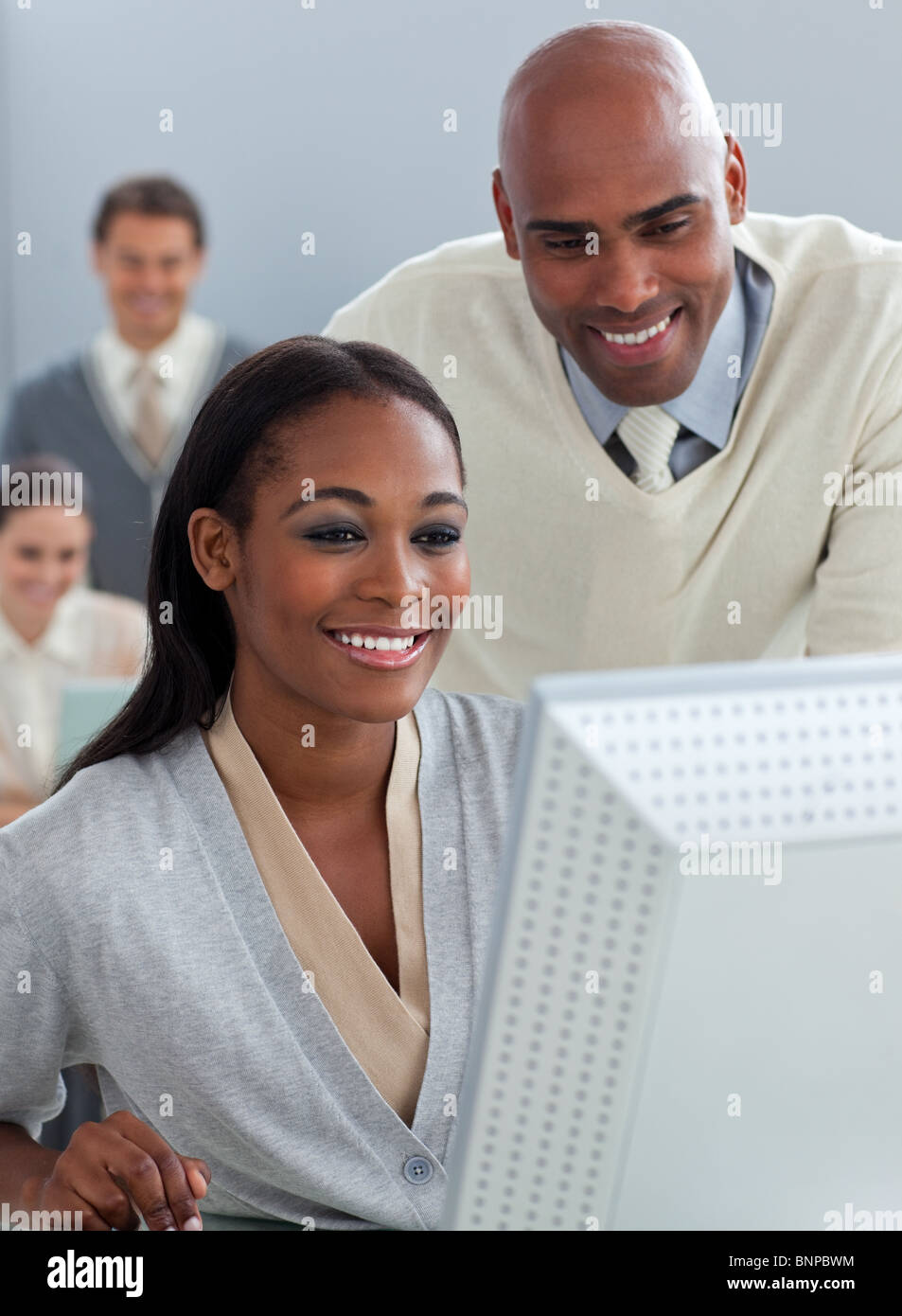 Confident businessman helping his colleague at a computer Stock Photo ...
