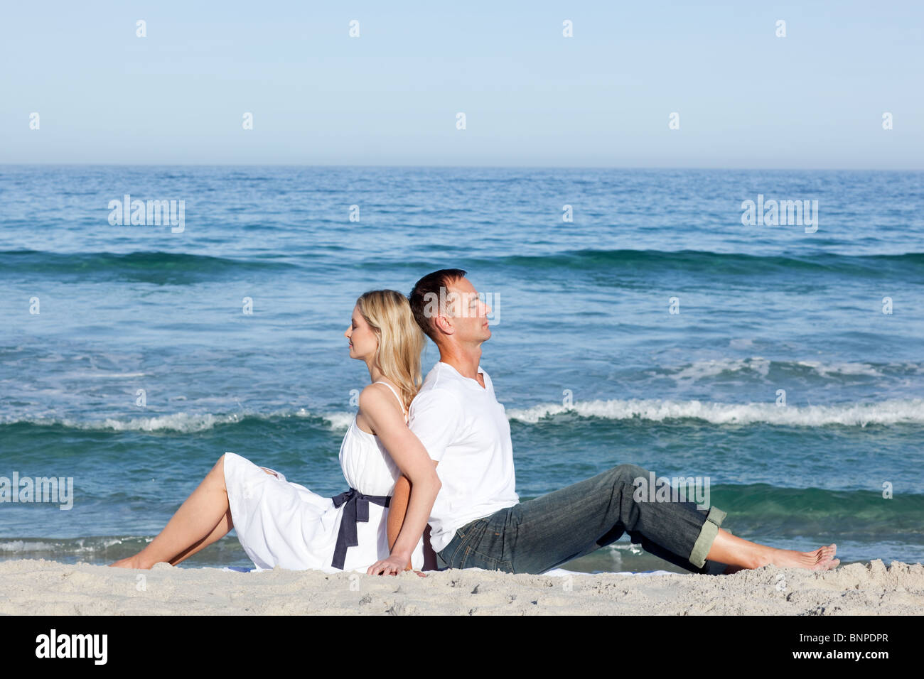Loving couple sitting on the sand Stock Photo - Alamy