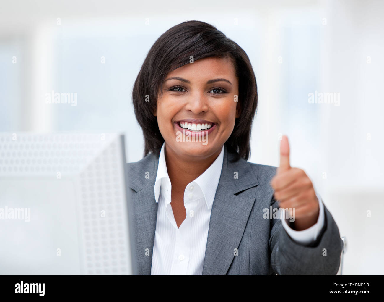 Happy businesswoman with a thumb up working at a computer Stock Photo ...
