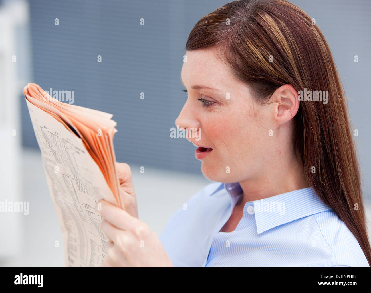 Surprised businesswoman reading newspaper Stock Photo - Alamy