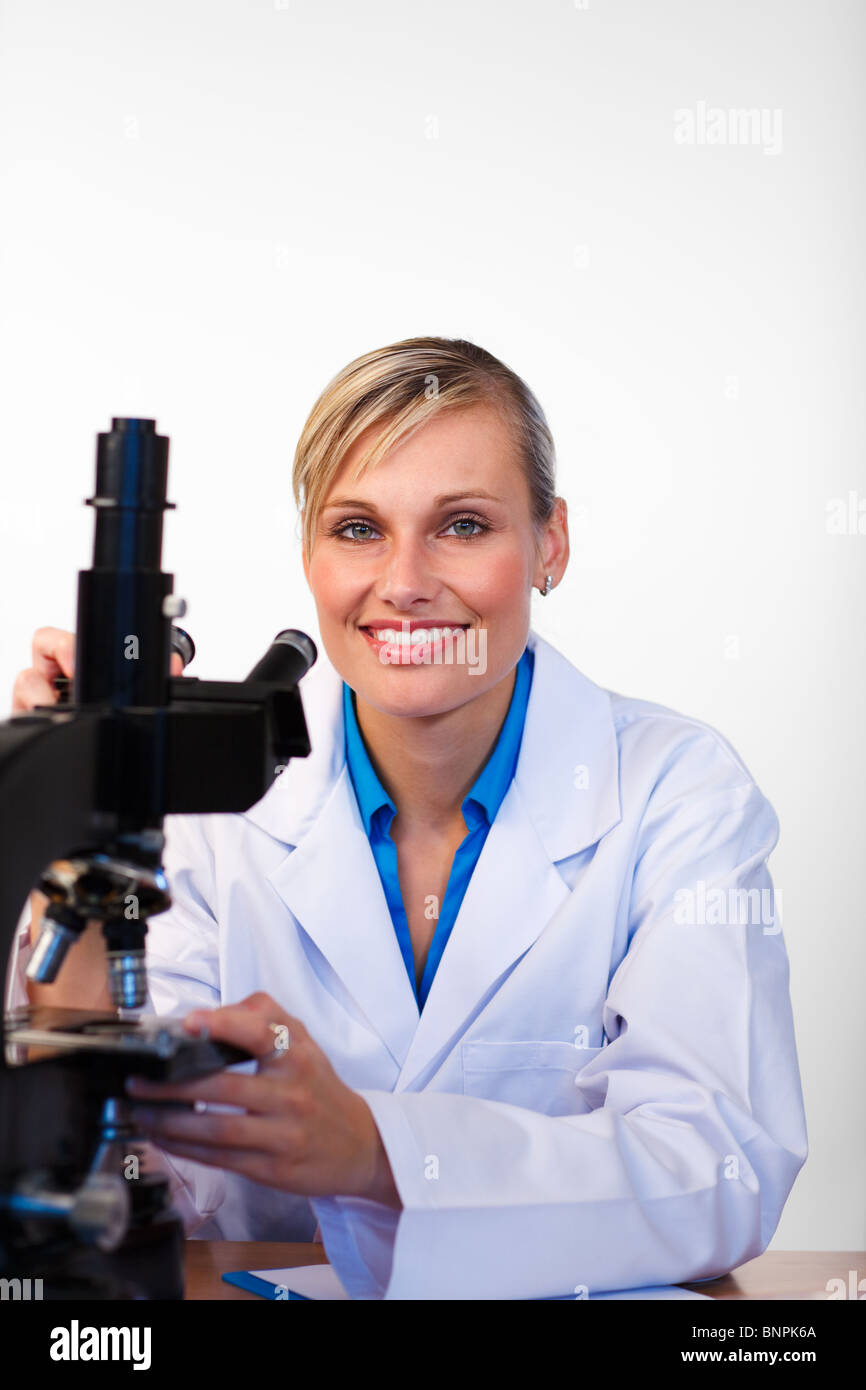 Blonde scientist with a microscope smiling at the camera in a ...