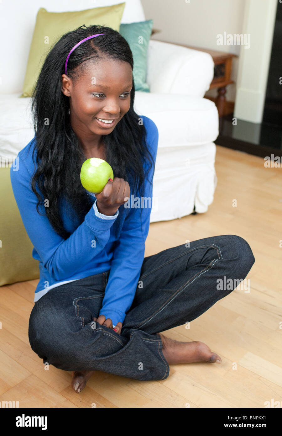 Jolly woman eating an apple sitting on the floor Stock Photo - Alamy