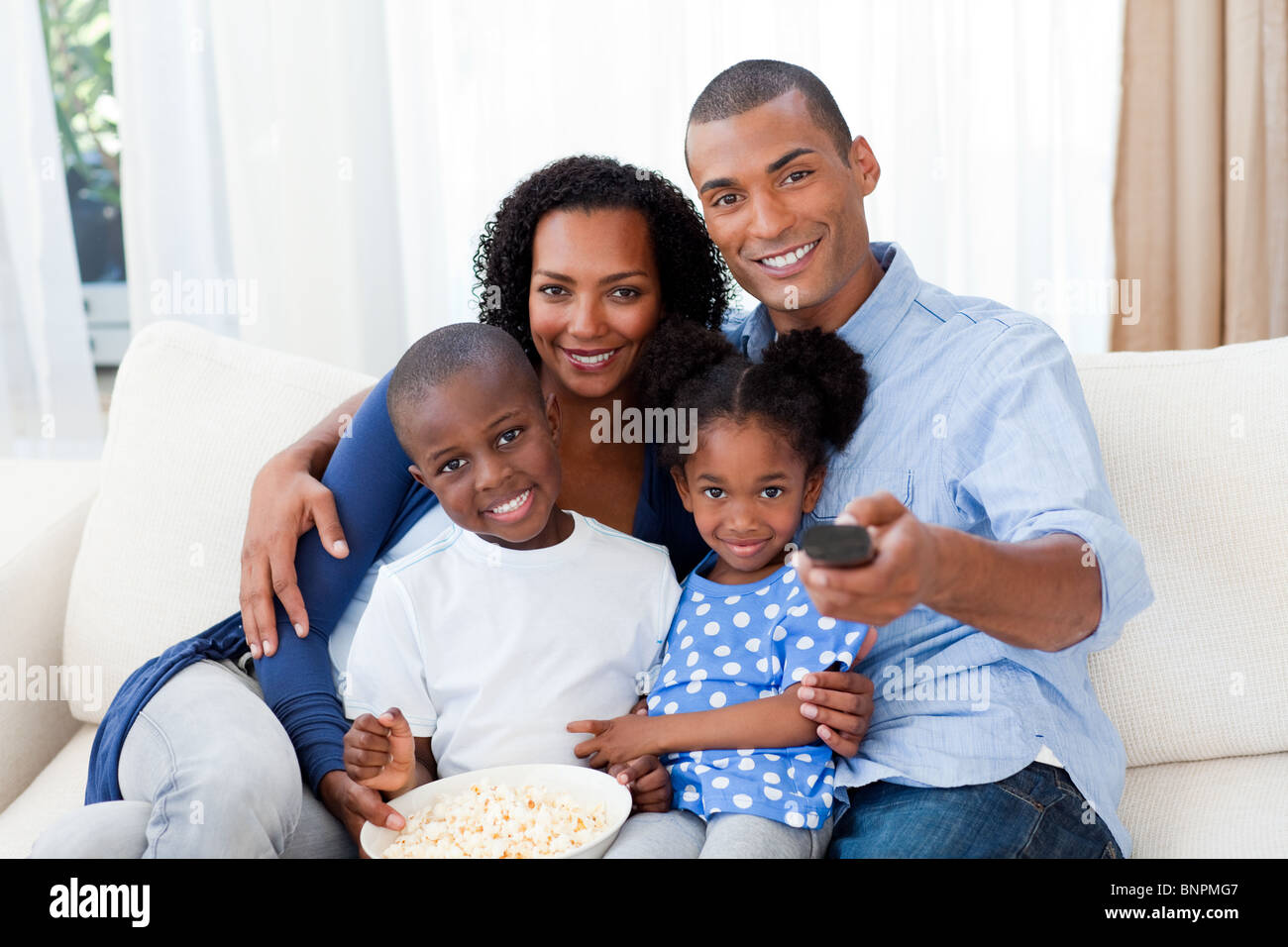 Smiling family eating popcorn and watching TV Stock Photo - Alamy