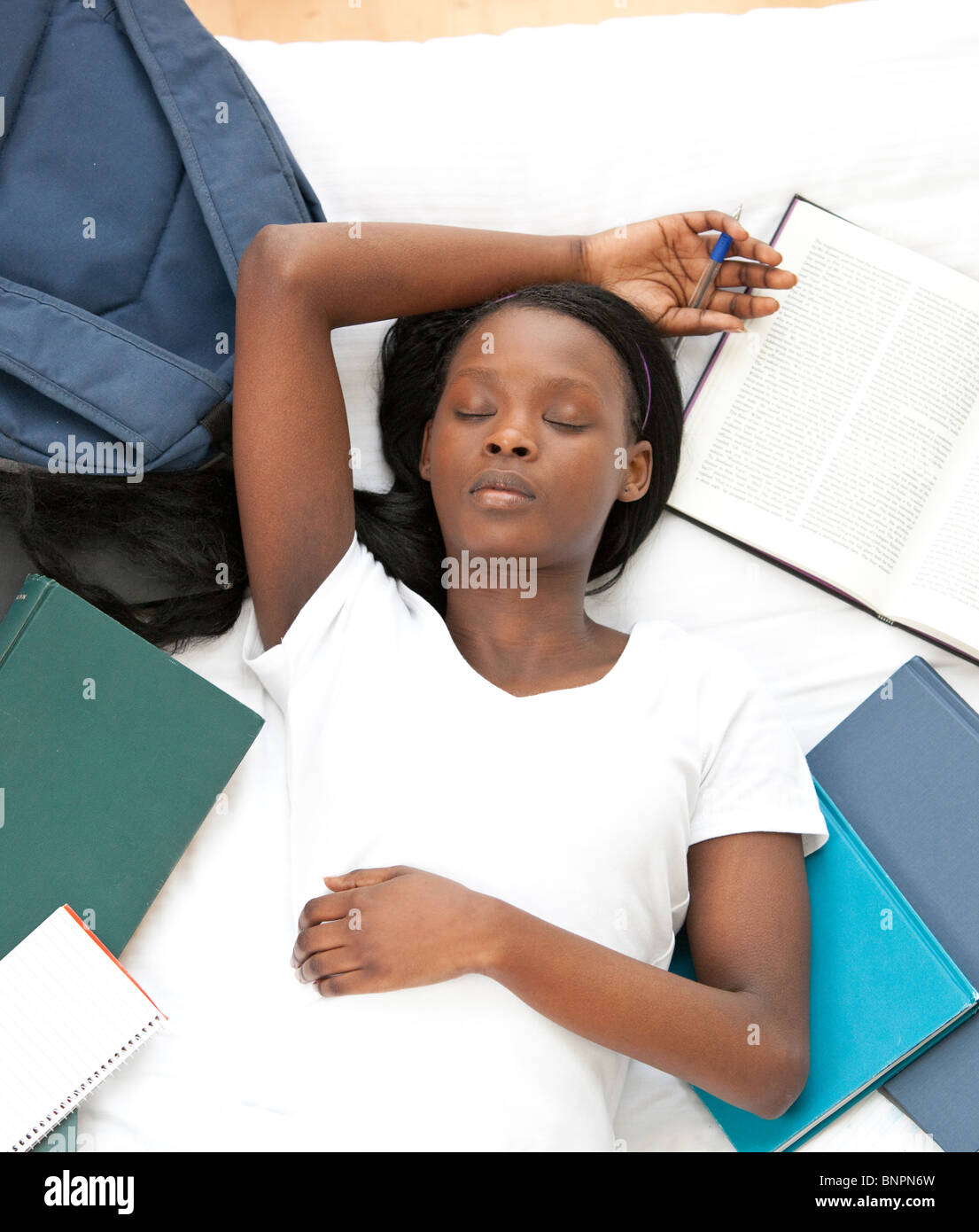 Tired student doing her homework lying on a bed Stock Photo - Alamy