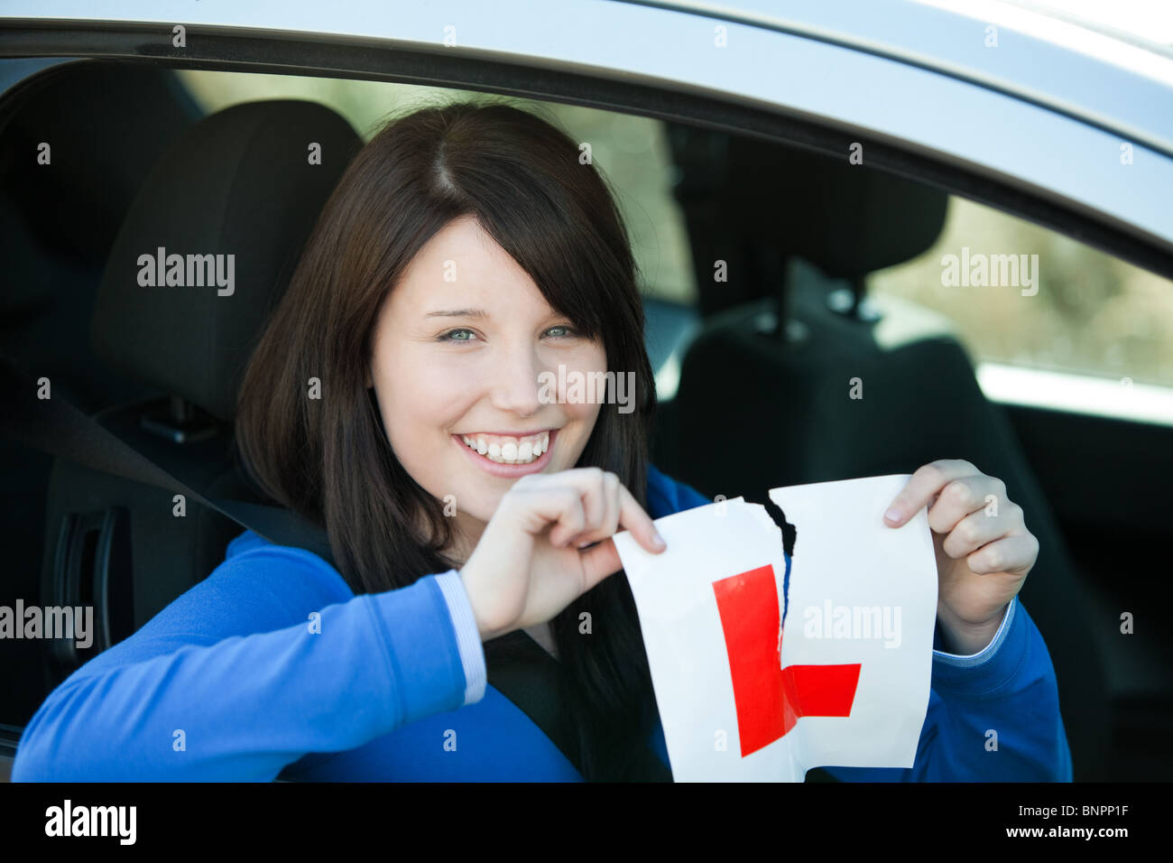 Jolly teen girl sitting in her car tearing a L-sign Stock Photo - Alamy