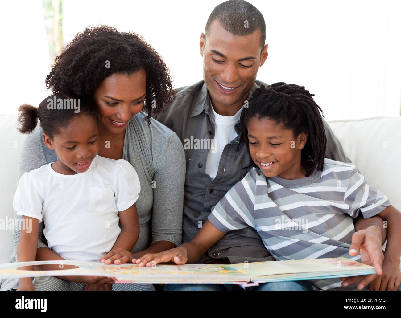 Family reading a book in the living-room Stock Photo - Alamy