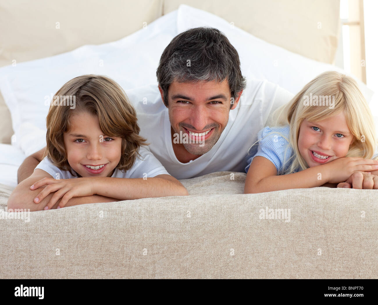 Caring father and his children lying on a bed Stock Photo - Alamy