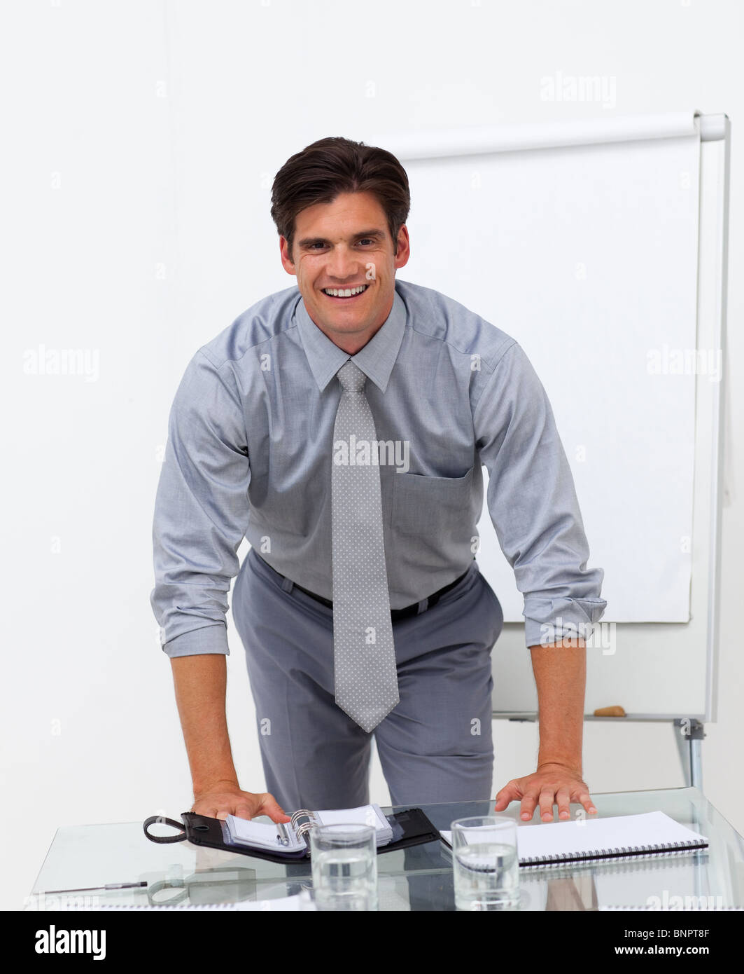 Cheerful businessman leaning on a conference table Stock Photo - Alamy