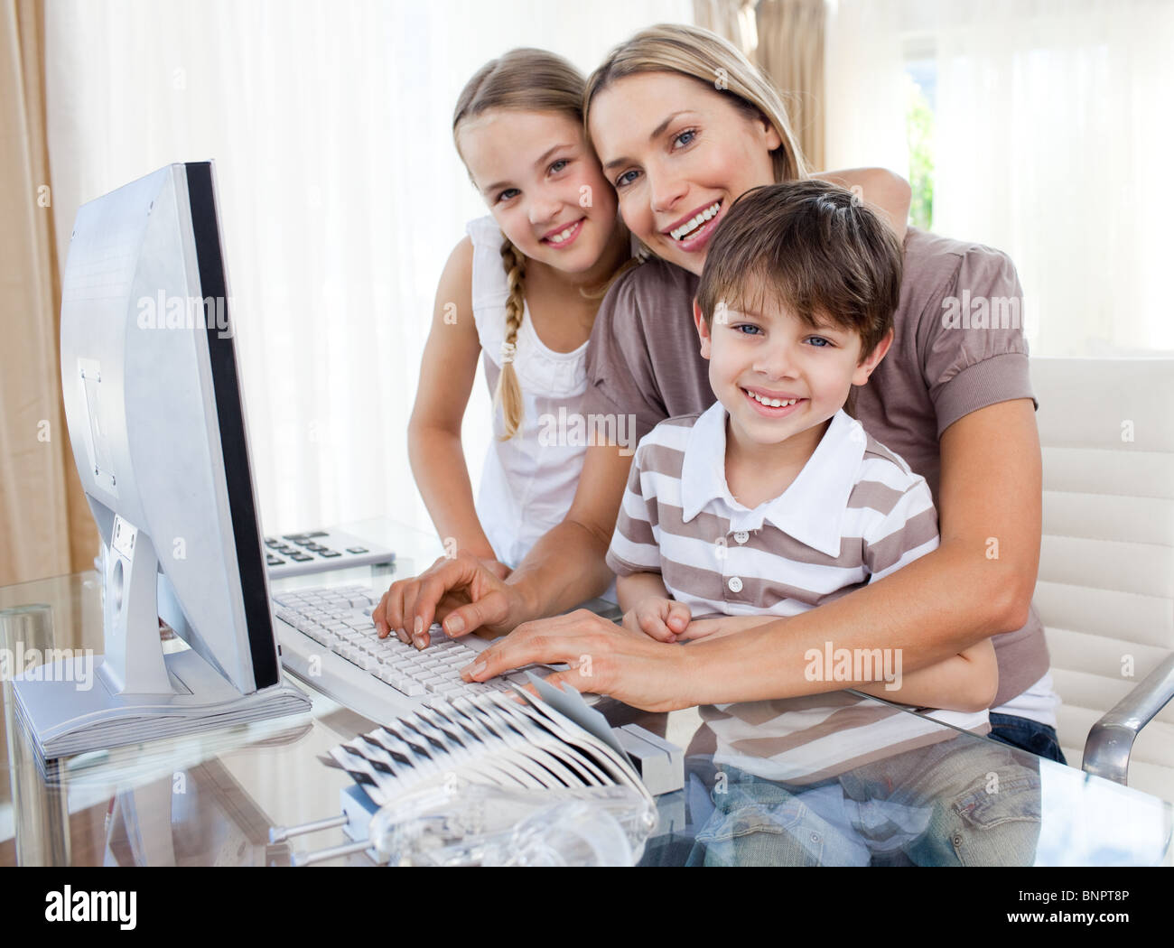 Attractive mother teaching her children how to use a computer Stock ...