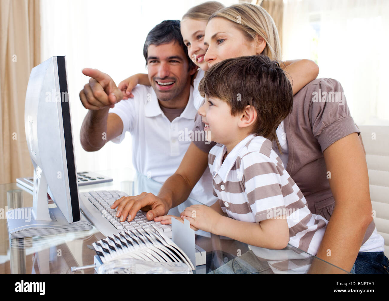 Children learning how to use a computer with their parents Stock Photo ...