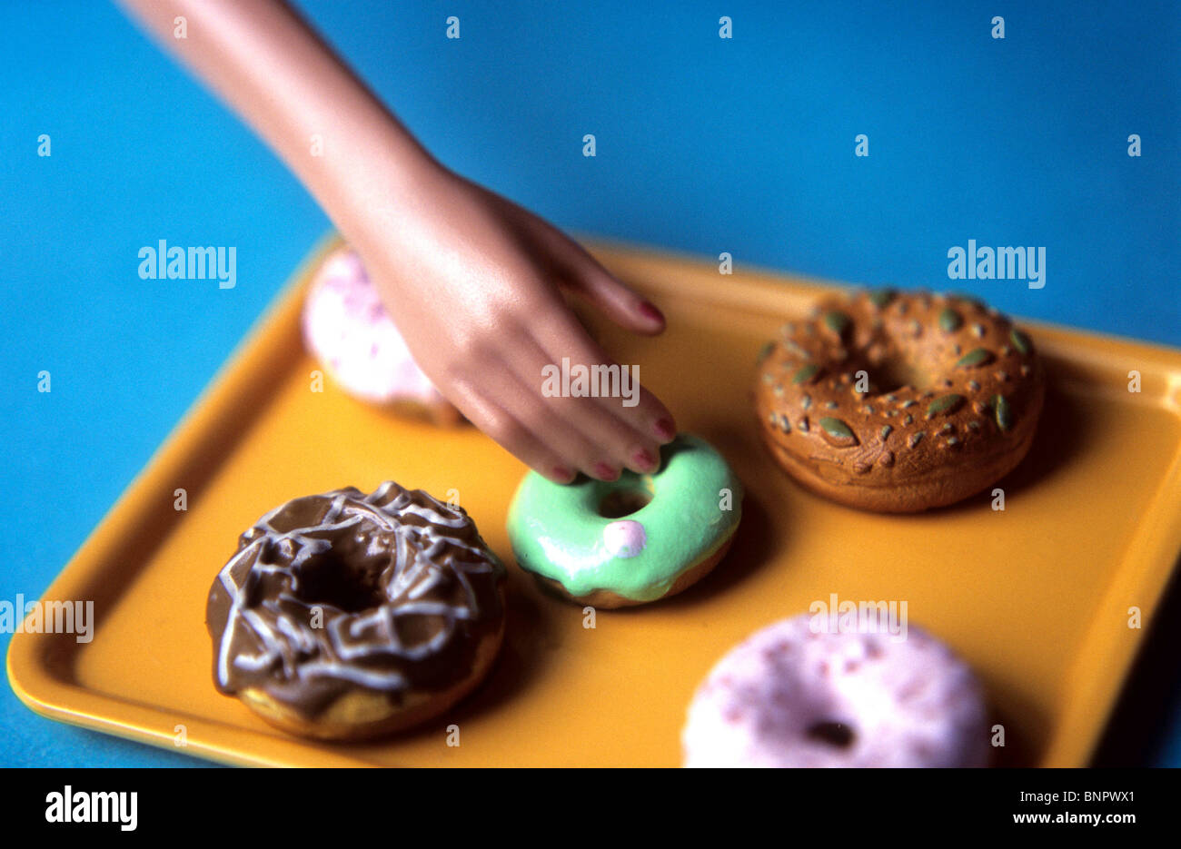 A woman's hand reaching for a donut Stock Photo - Alamy