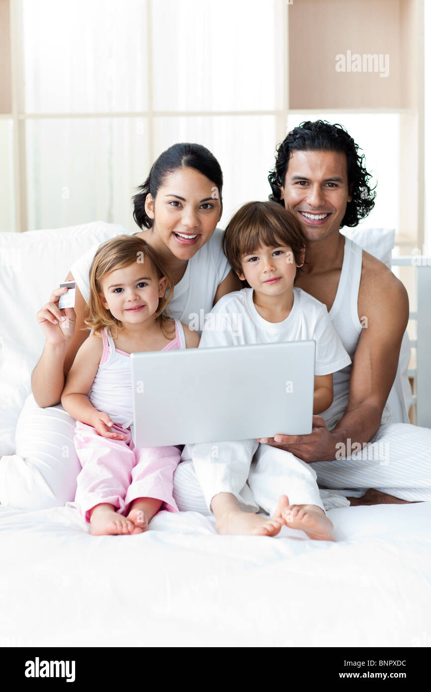 Young family using a laptop on the bed Stock Photo - Alamy