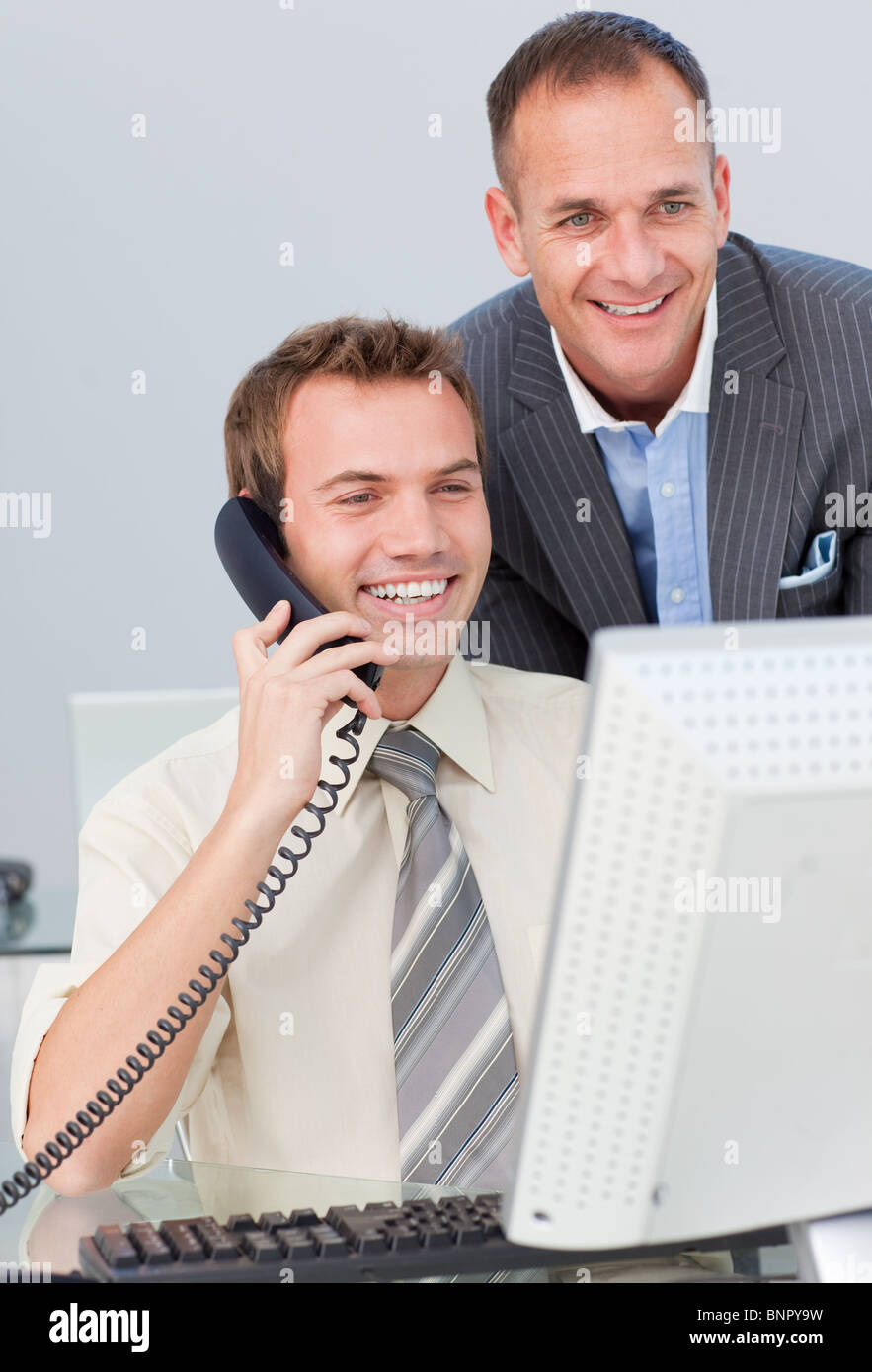 Businessman on phone and working with his colleague Stock Photo - Alamy