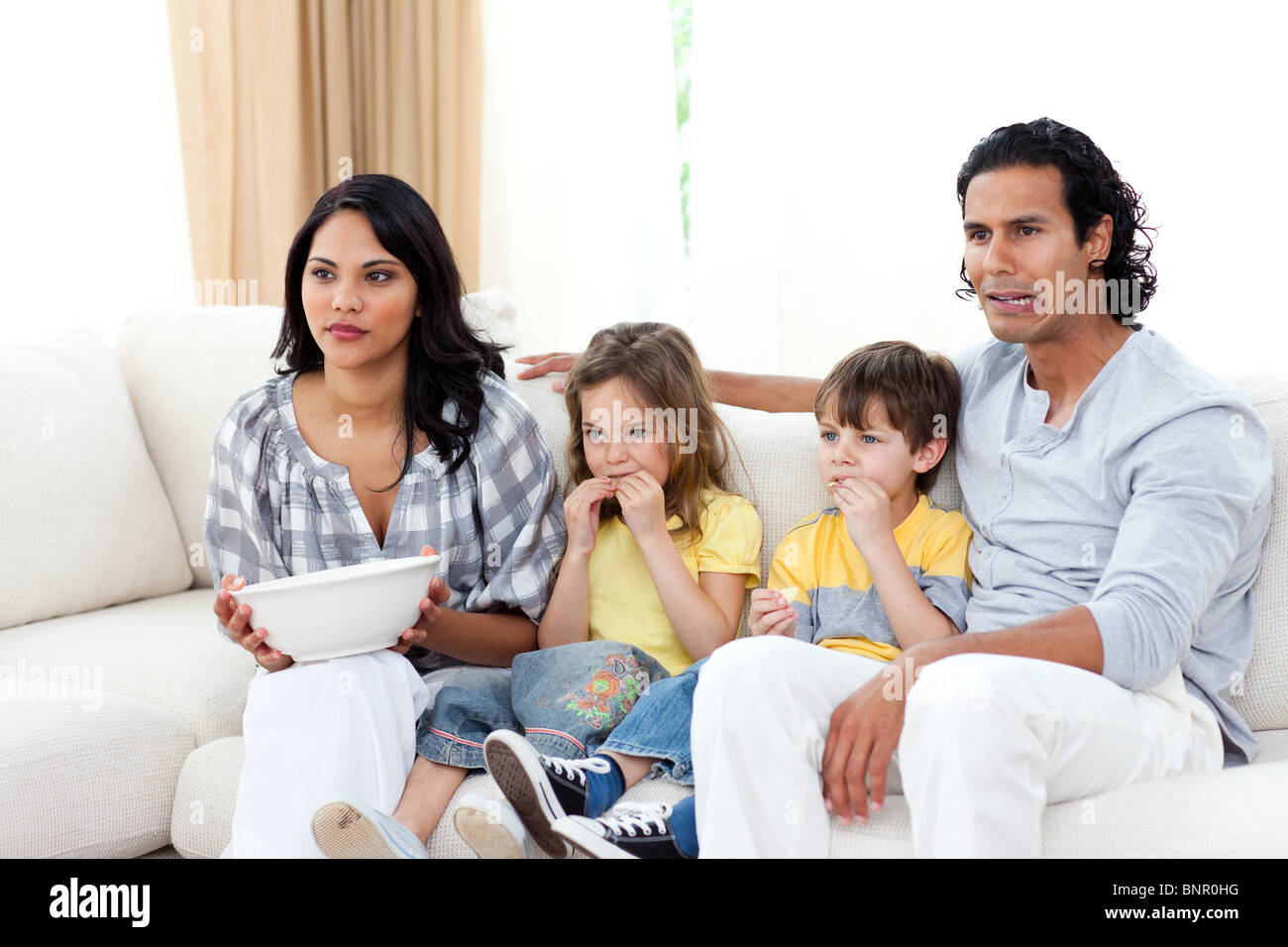 Concentrated family watching TV on sofa Stock Photo - Alamy