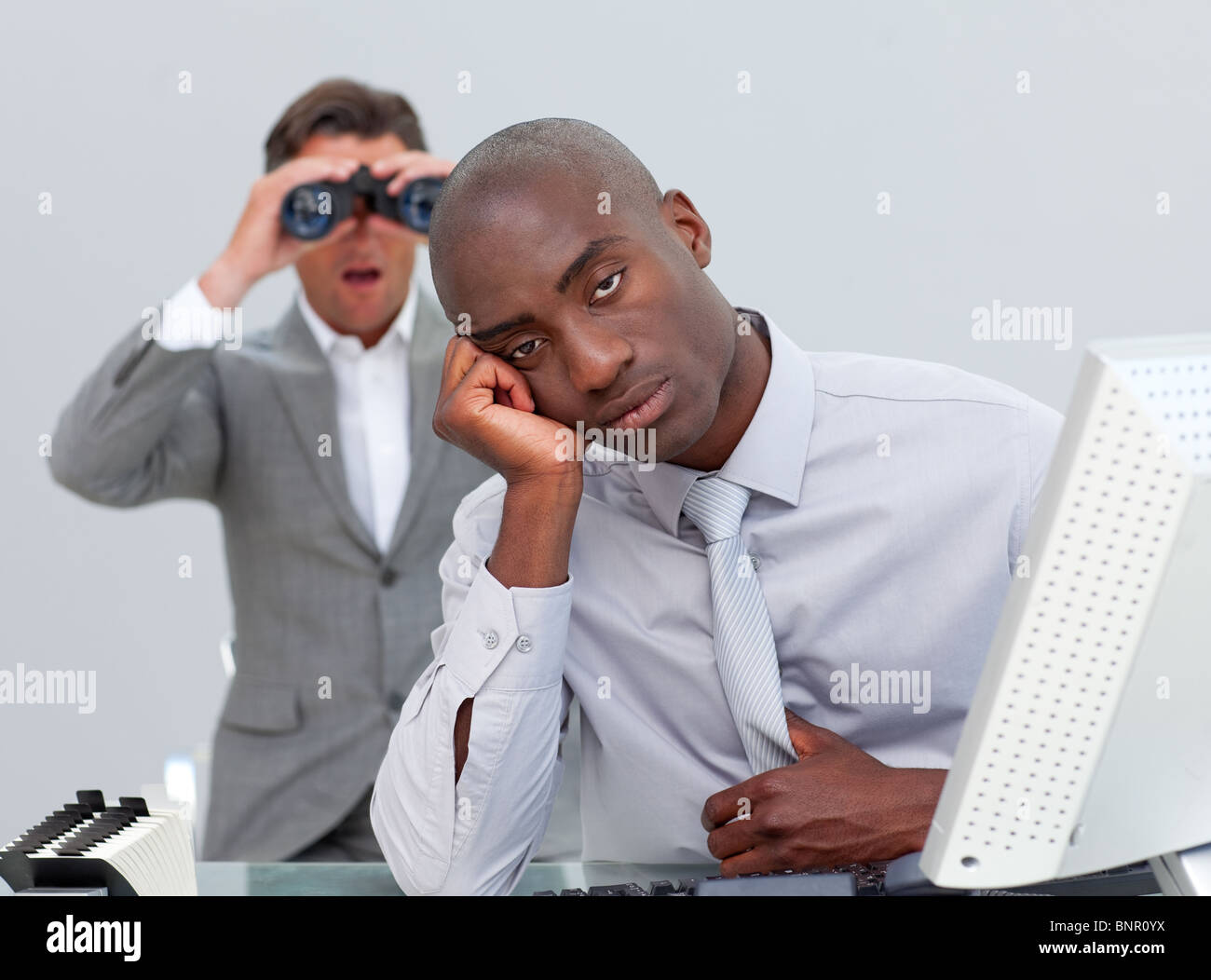 Businessman getting bored and his manager looking through binoculars ...