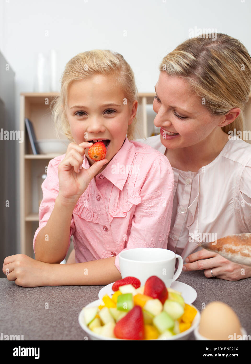 Attractive mother eating fruit with her daughter Stock Photo - Alamy