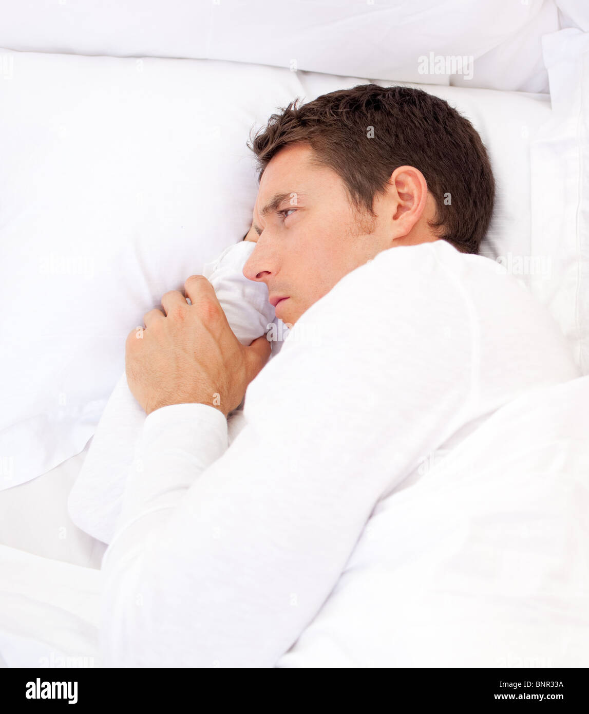 Portrait of a sad man lying in bed Stock Photo - Alamy
