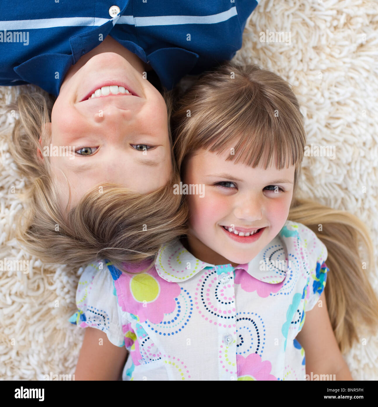 Adorable siblings lying on the floor Stock Photo - Alamy