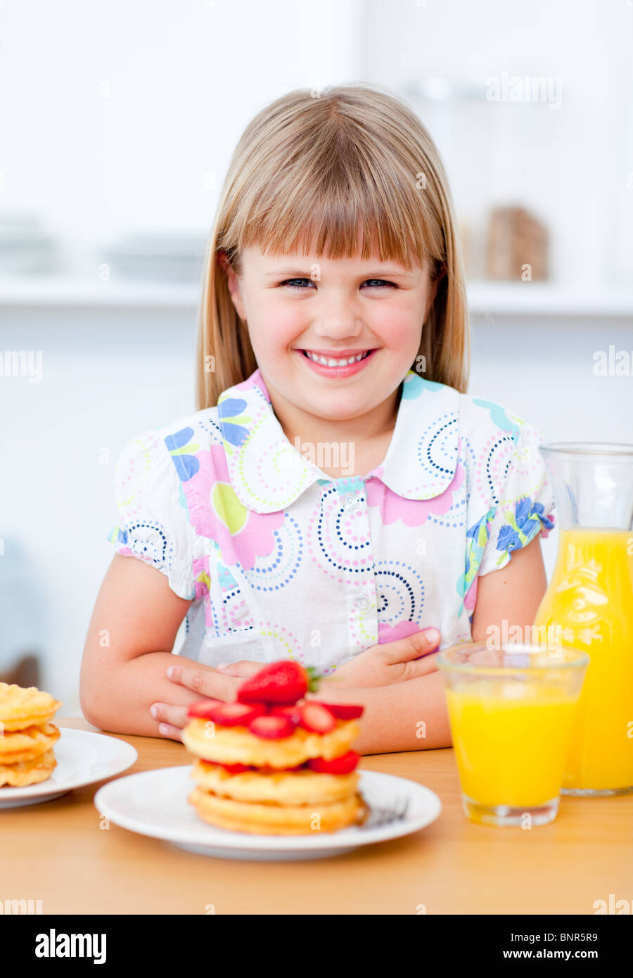 Joyful little girl eating waffles with strawberries Stock Photo - Alamy