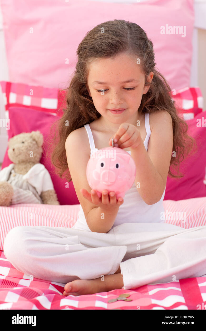 Smiling girl saving money in a piggybank Stock Photo - Alamy
