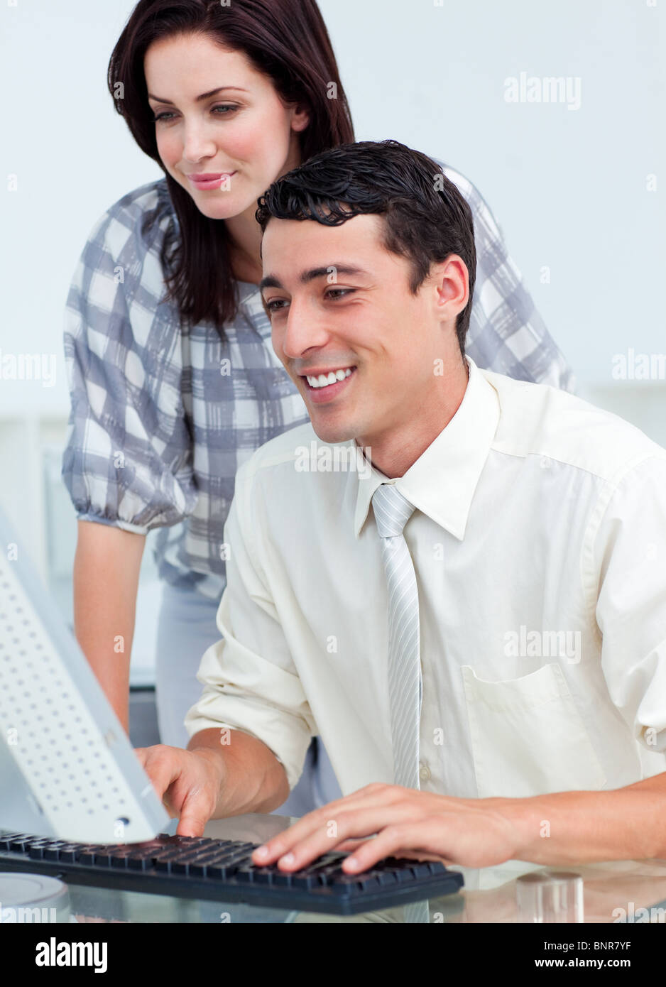 Attractive businesswoman helping her colleague at a computer Stock ...