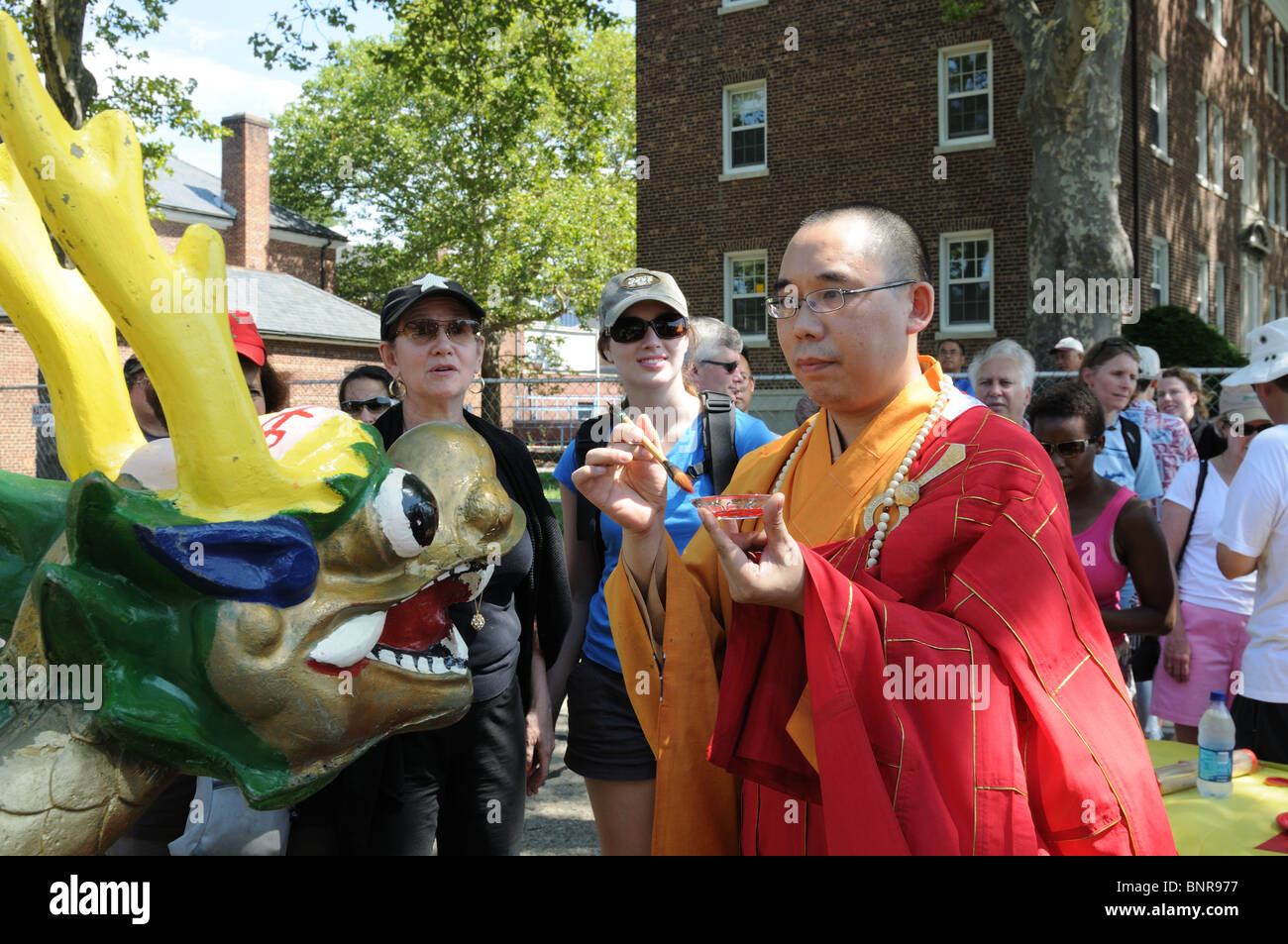 A Buddhist monk painting a red spot on the eye of the dragon figurehead ...
