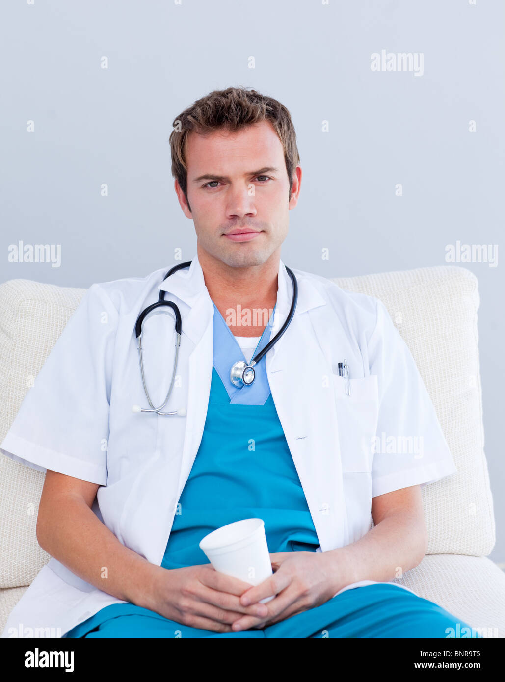 Serious male doctor drinking coffee Stock Photo - Alamy