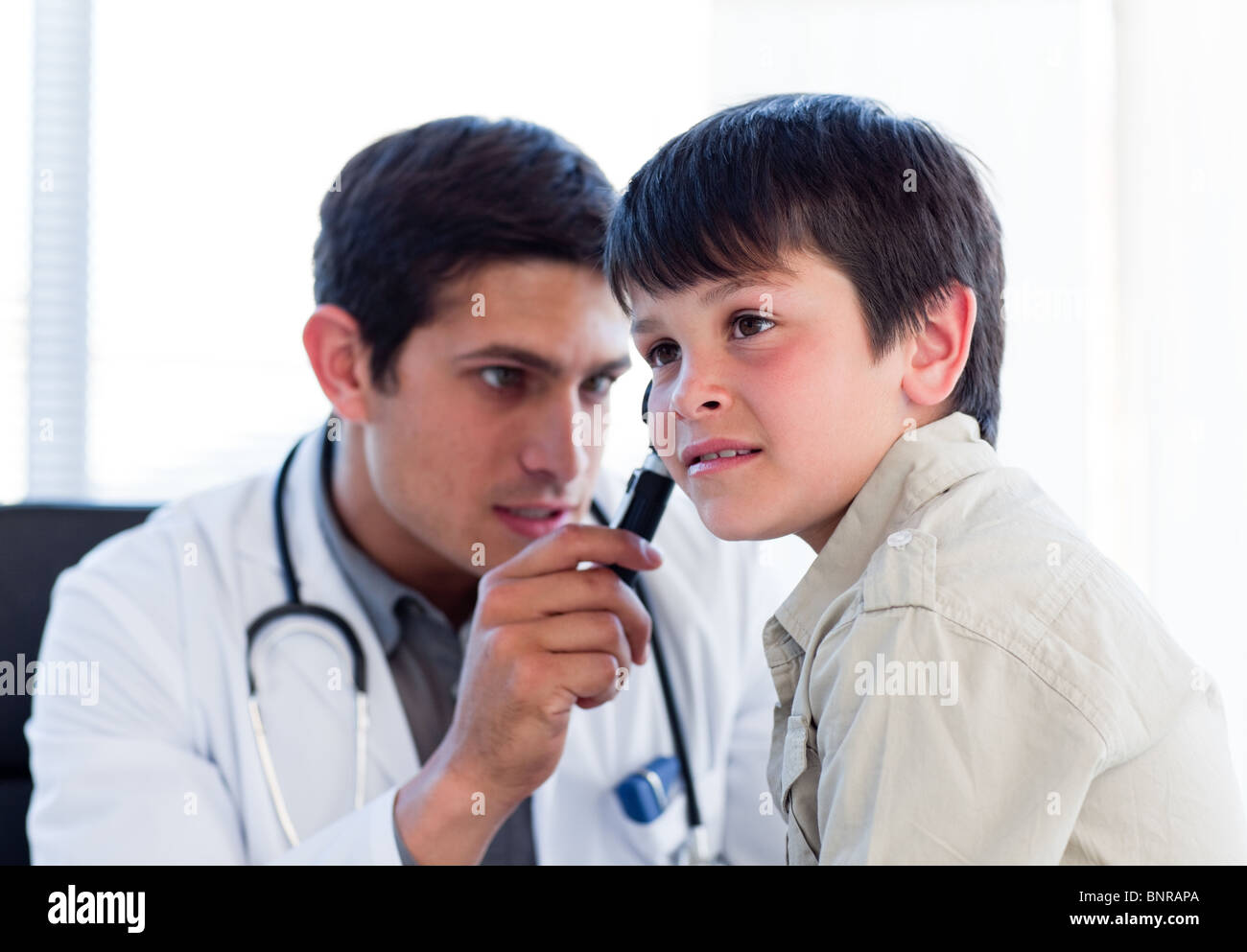 Young doctor examining little boy's ears Stock Photo - Alamy
