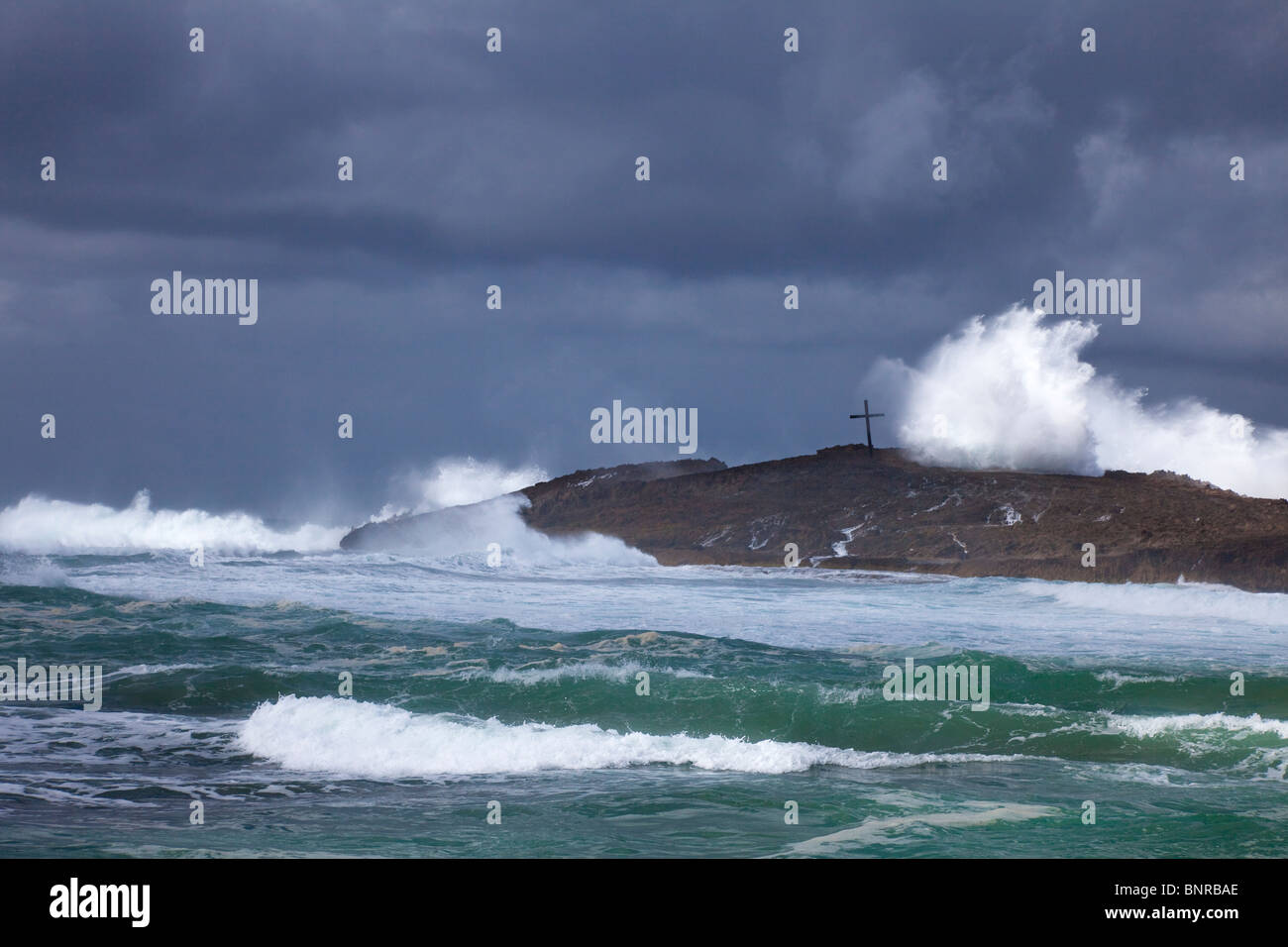 A small island and a cross with surf waves off the north coast of ...
