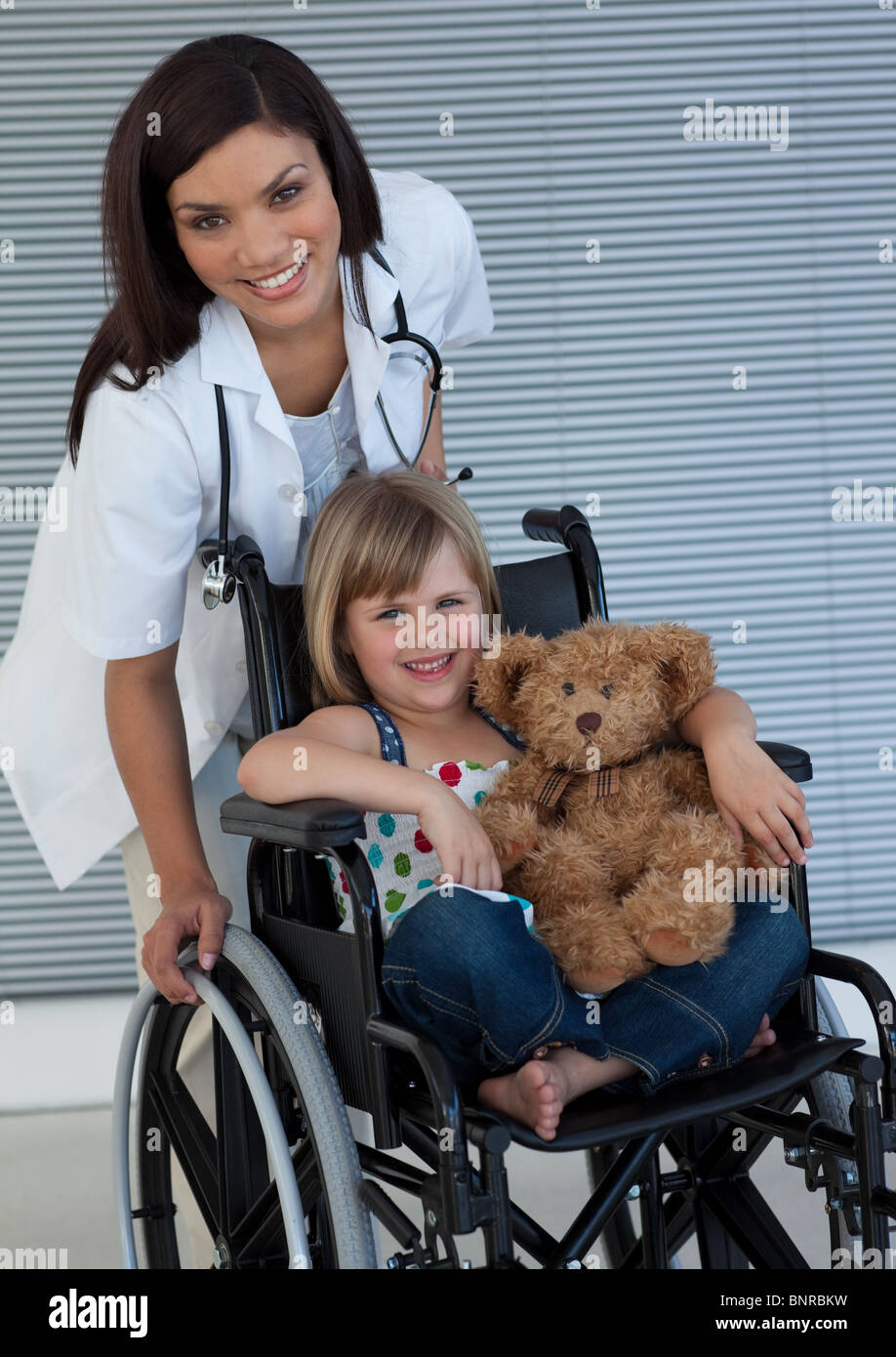 Little girl on a wheelchair holding her teddy bear Stock Photo - Alamy