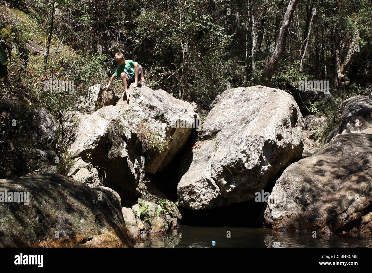 Young boy sitting on a rock above pool of water in Queensland ...