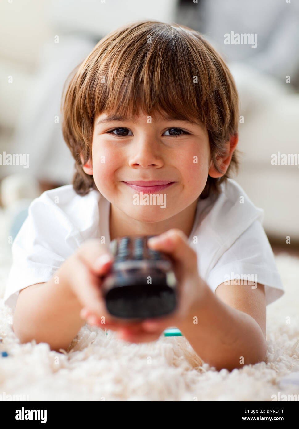 Smiling little boy watching TV lying on the floor Stock Photo - Alamy