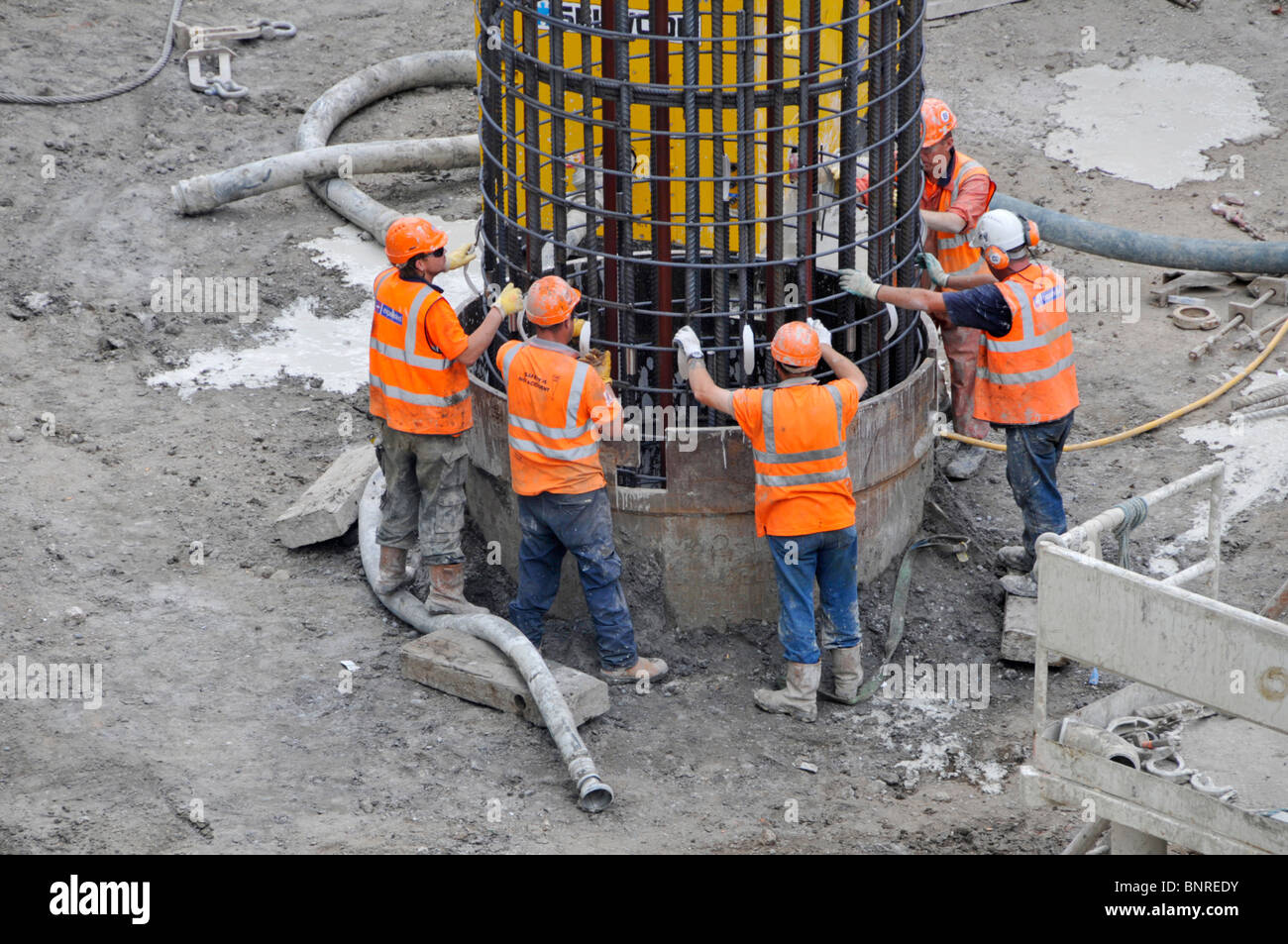 Steel reinforcing cage being put in place by crane into pile casing ...